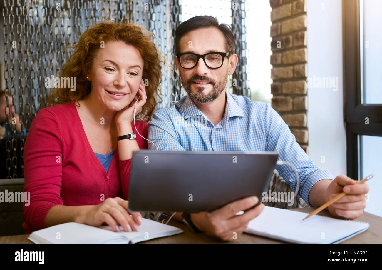 Smiling workmates using modern gadget in the cafe Stock Photo - Alamy