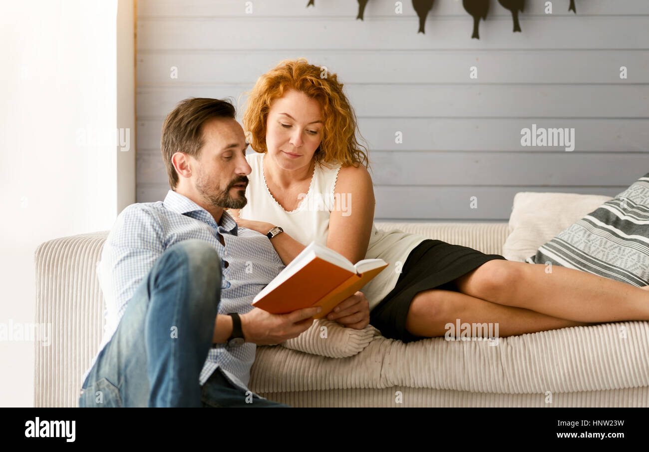 Lovely couple reading book together at home Stock Photo - Alamy