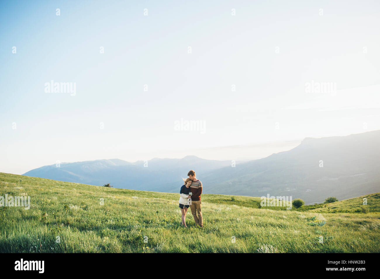 Caucasian couple hugging in field Stock Photo - Alamy