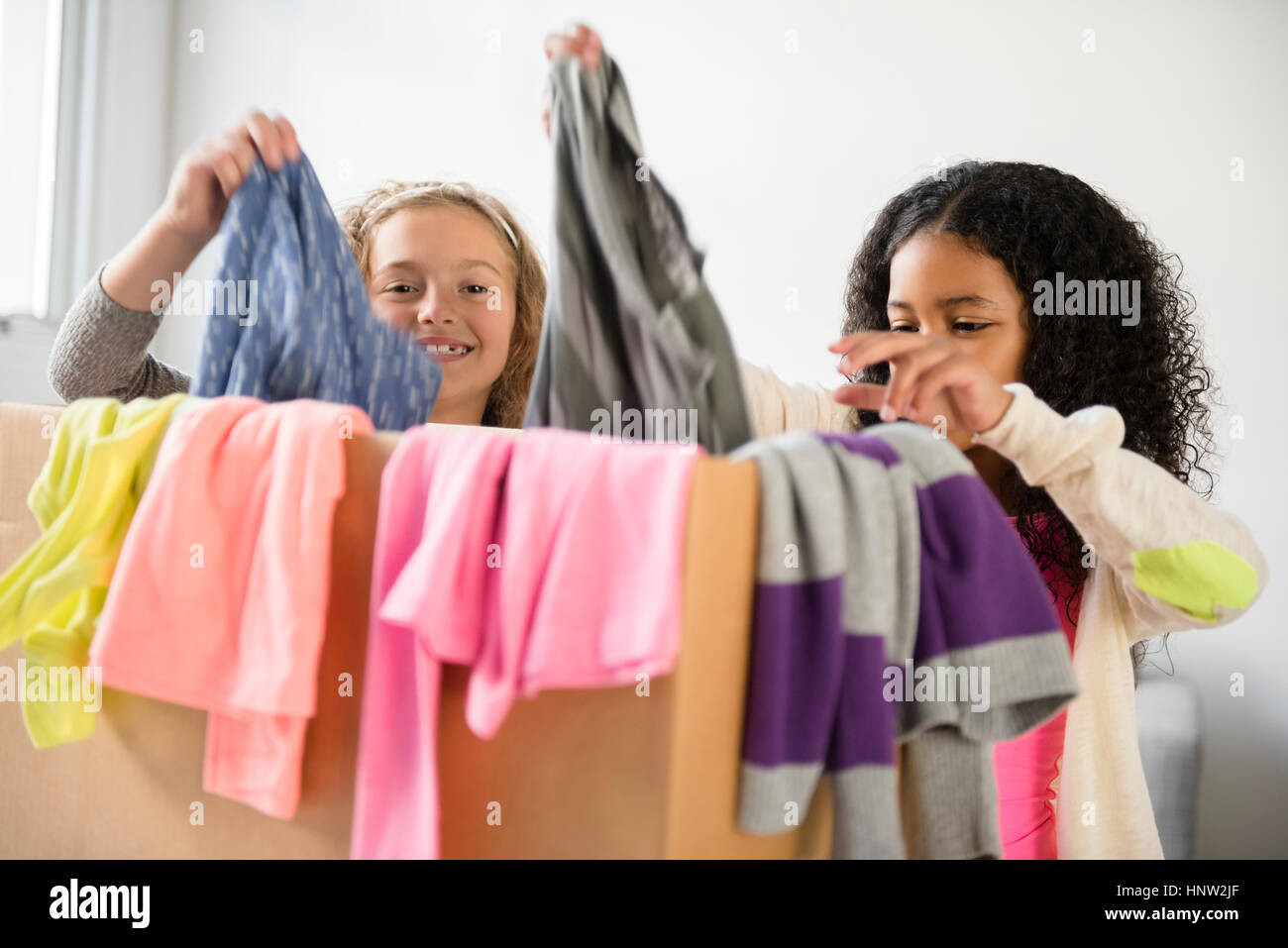 Girls examining box of clothing Stock Photo - Alamy