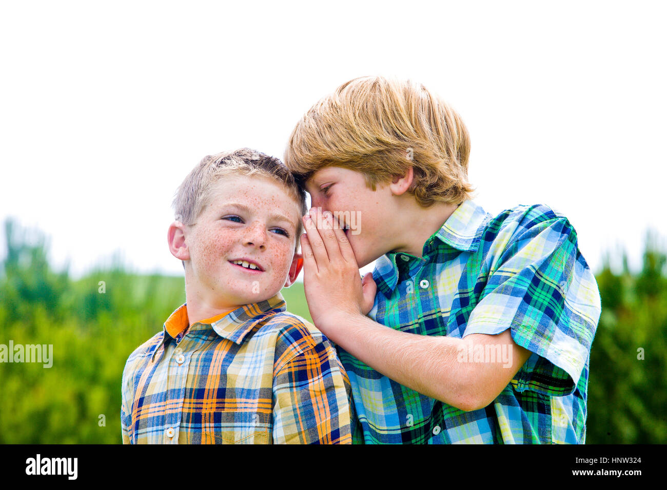 Caucasian boy whispering to brother Stock Photo - Alamy