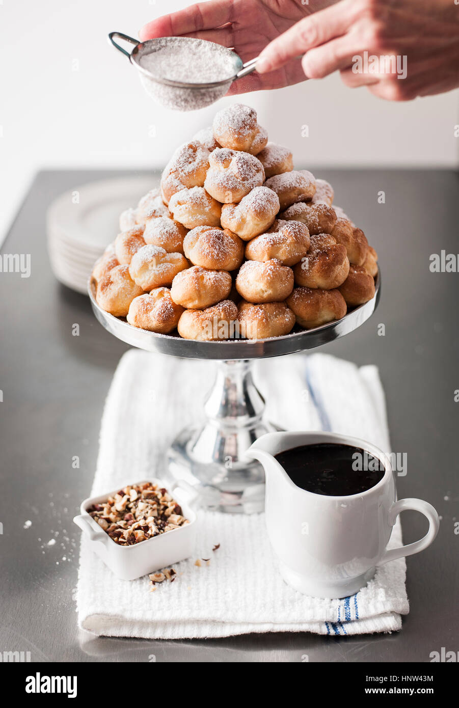 Hands shaking powdered sugar onto tray of cream puffs Stock Photo - Alamy