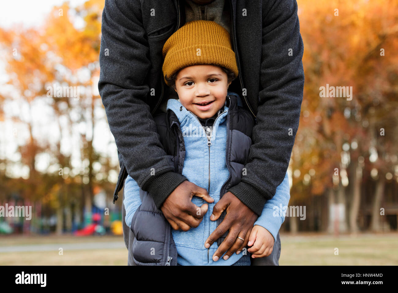 Father leaning over son in park Stock Photo - Alamy