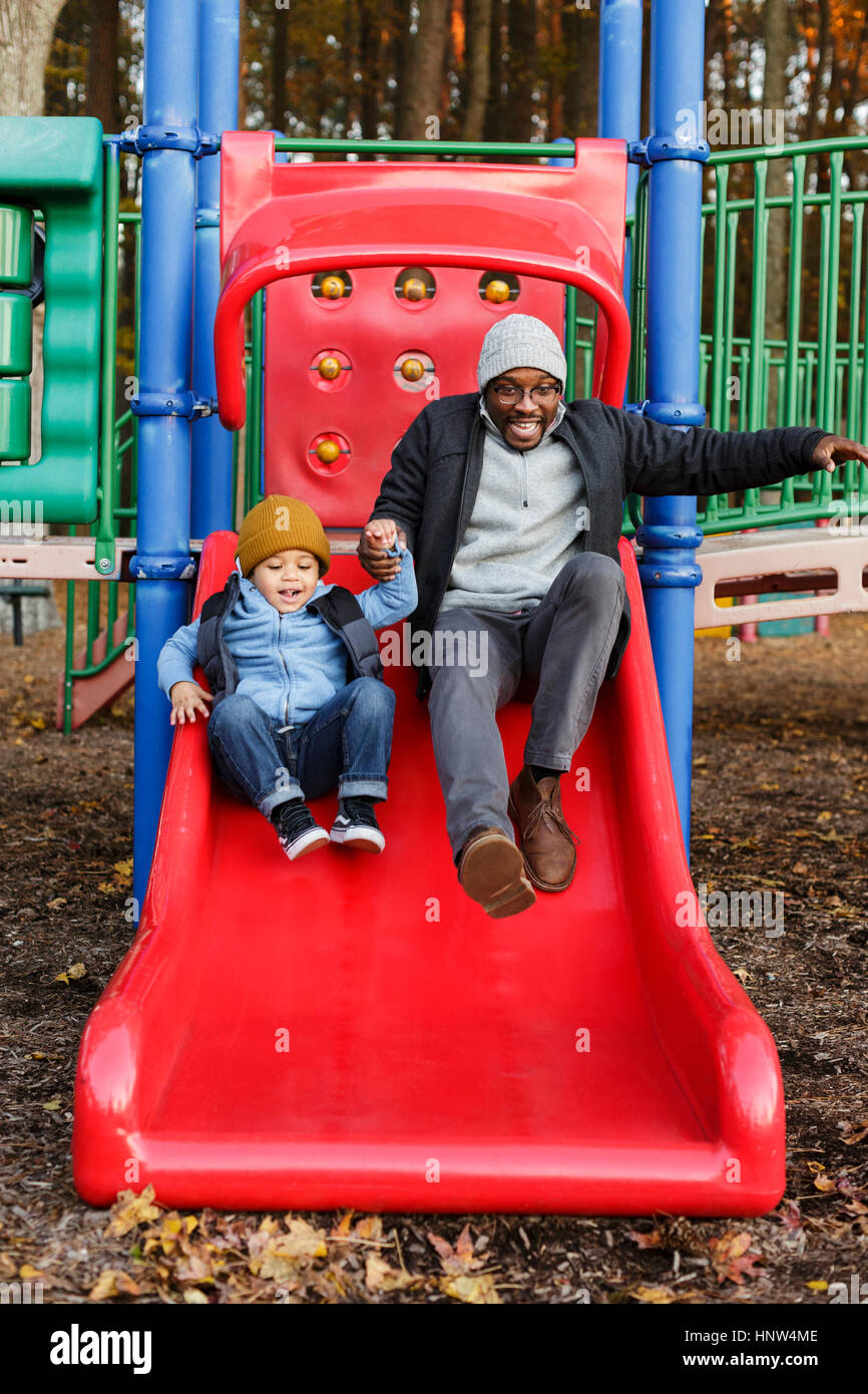Father and son on playground slide in park Stock Photo - Alamy