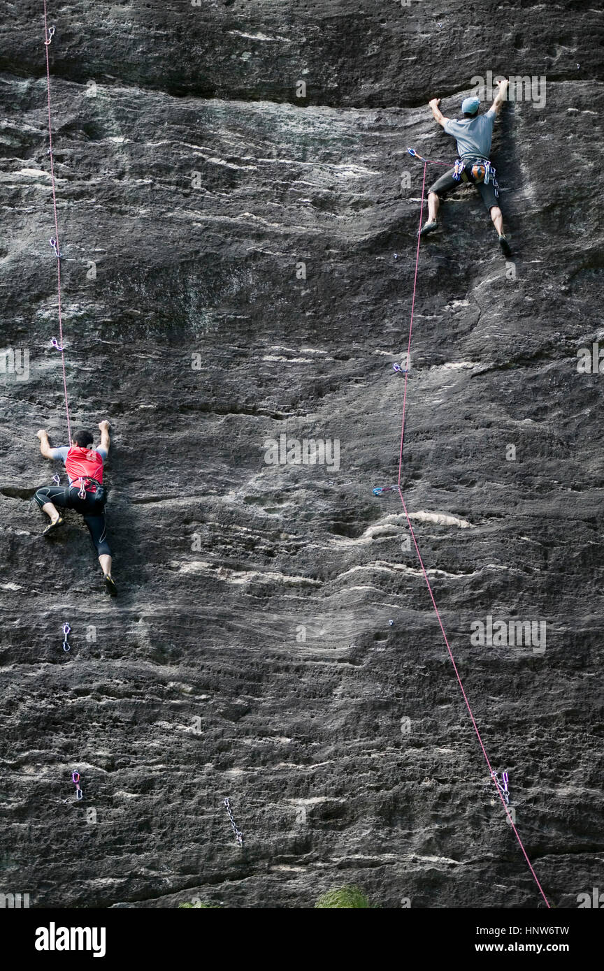 Rock climbers climbing rock face Stock Photo - Alamy