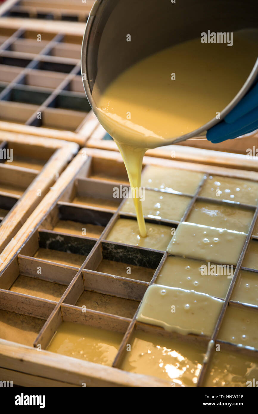 Saucepan pouring liquid lavender soap into moulds in handmade soap ...
