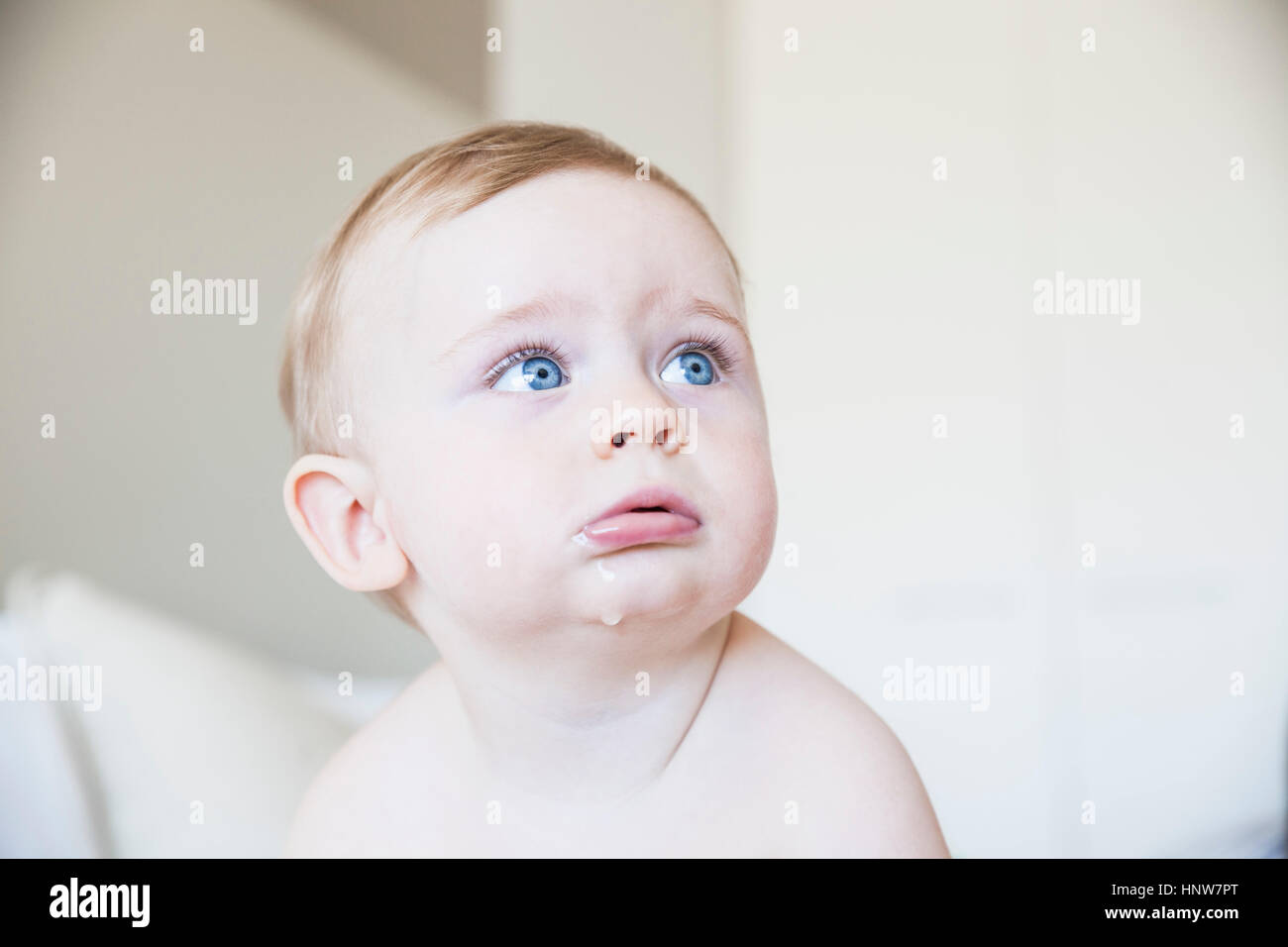 Portrait of blue eyed dribbling baby boy looking up from bed Stock ...