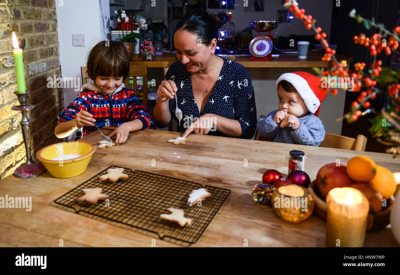 Mother and two sons at table icing home-baked Christmas biscuits Stock ...