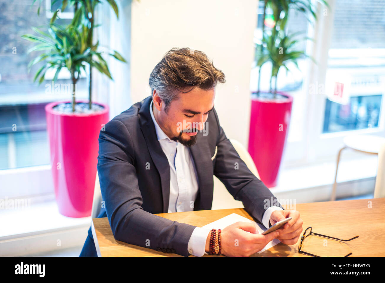 Businessman at office desk reading smartphone texts Stock Photo - Alamy