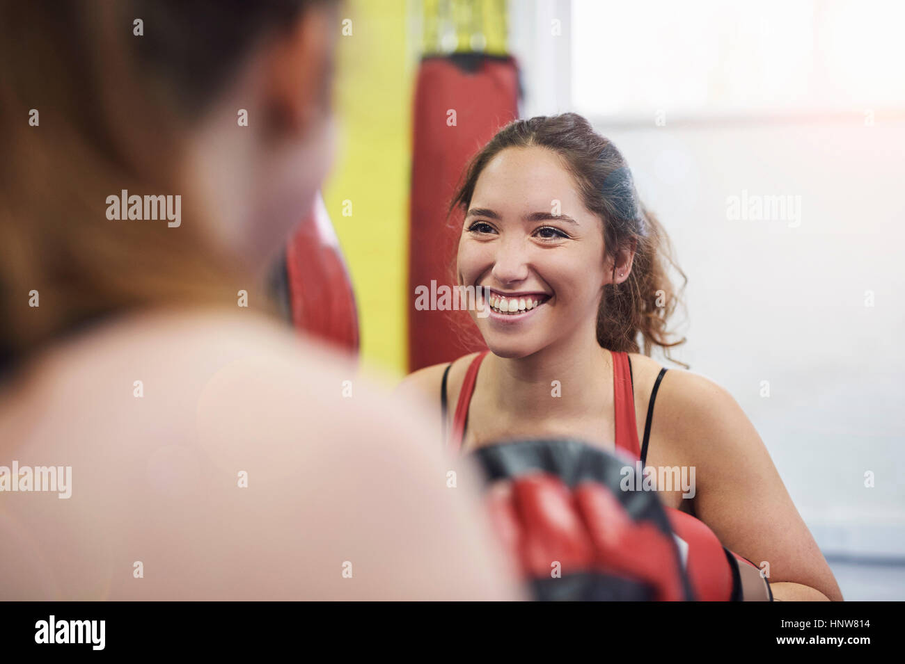 Over shoulder view of female boxer training, punching teammates punch ...