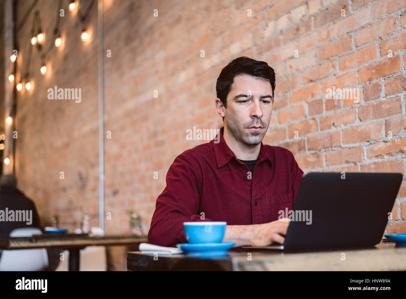 Man working on laptop at cafe Stock Photo - Alamy