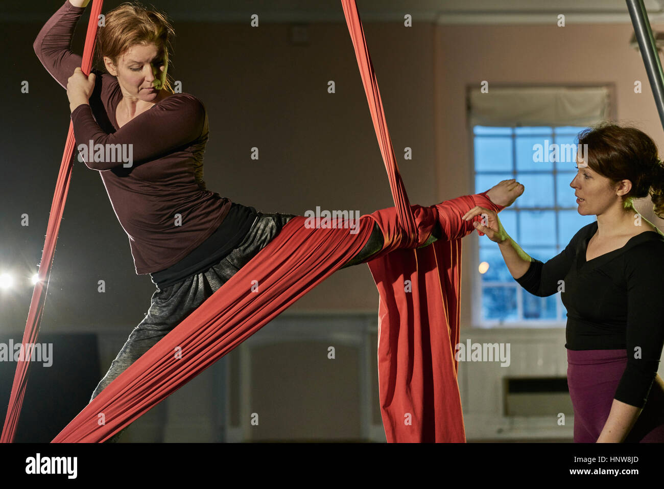 Two young female aerial acrobats practicing the splits on silk rope ...
