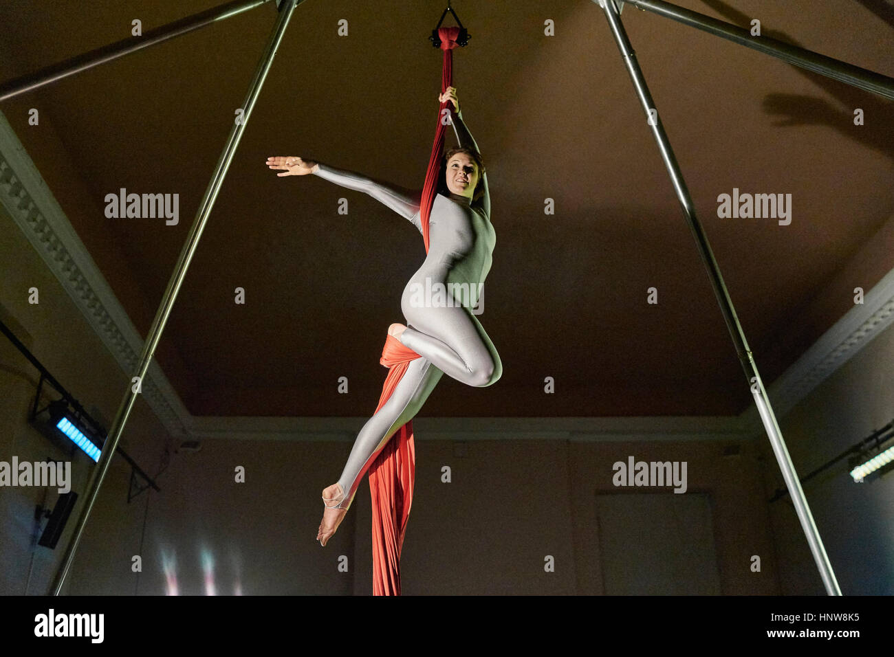 Low angle view of young female aerial acrobat on red silk ropes Stock ...