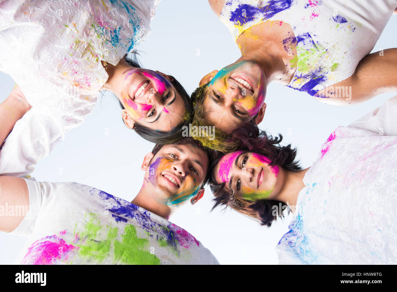 4 smart young indian people celebrating holi, standing isolated over ...