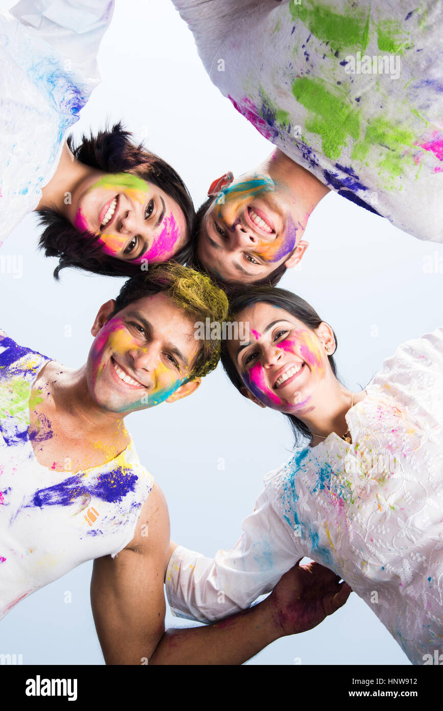 4 smart young indian people celebrating holi, standing isolated over ...