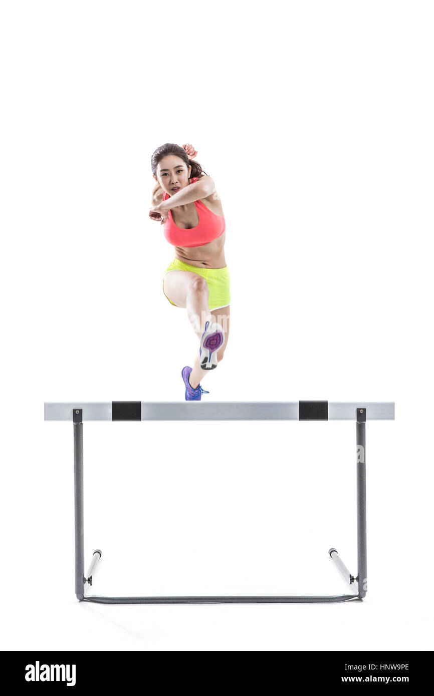 Dynamic female athlete jumping over obstacle Stock Photo - Alamy