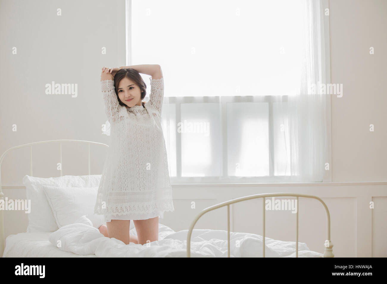 Young smiling woman stretching in bed Stock Photo - Alamy