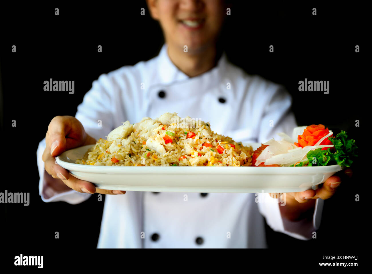 Smiling Chef proudly presenting crab fried rice in dark dramatic ...