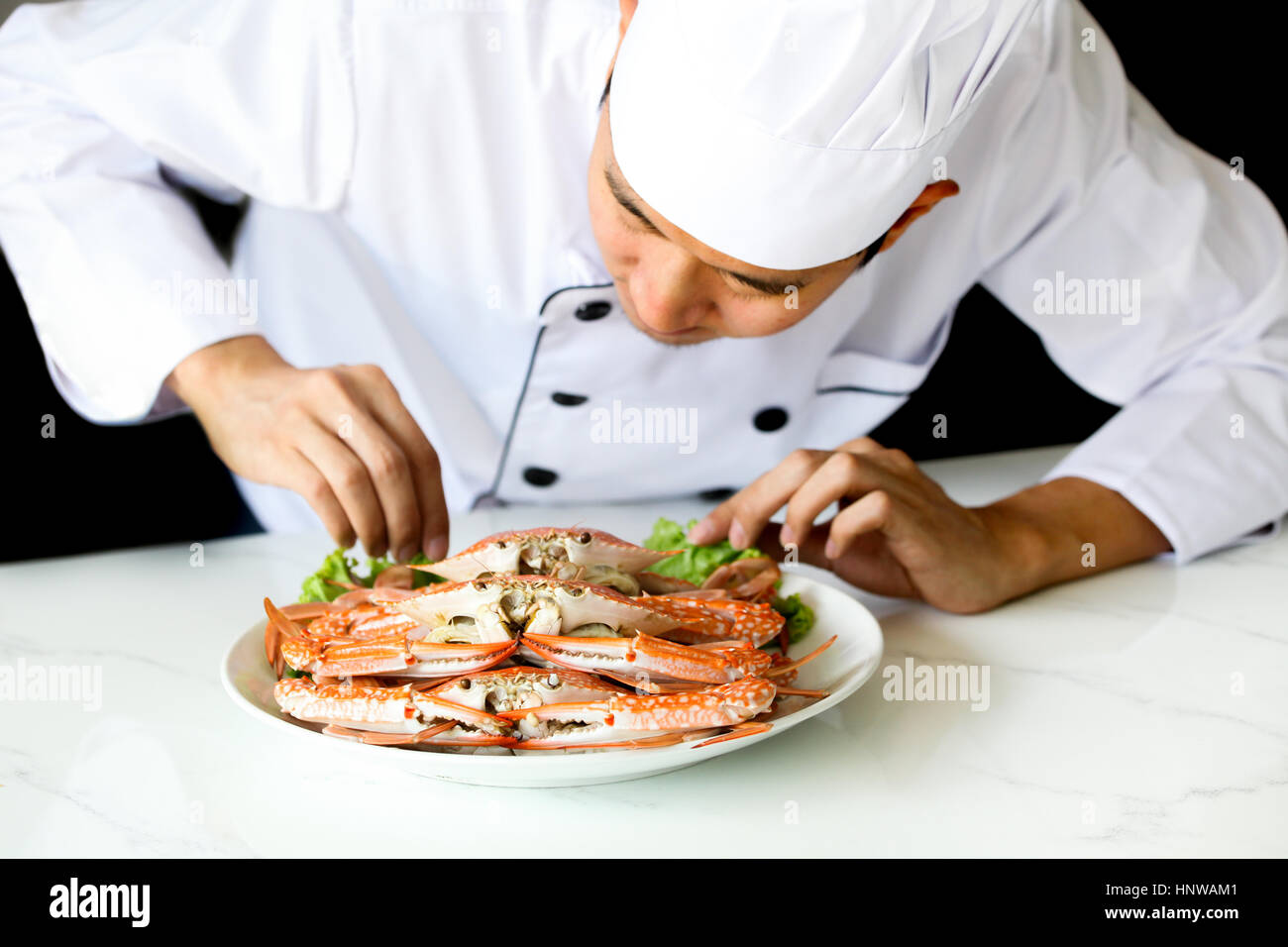 Asian chef preparing and decorating grilled crab seafood meal with ...
