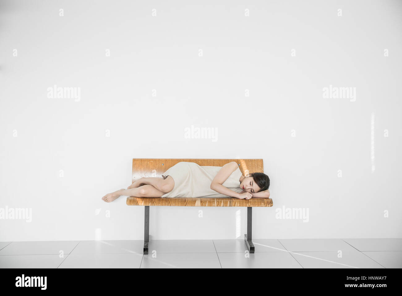 Young woman depressed lying down on bench Stock Photo - Alamy