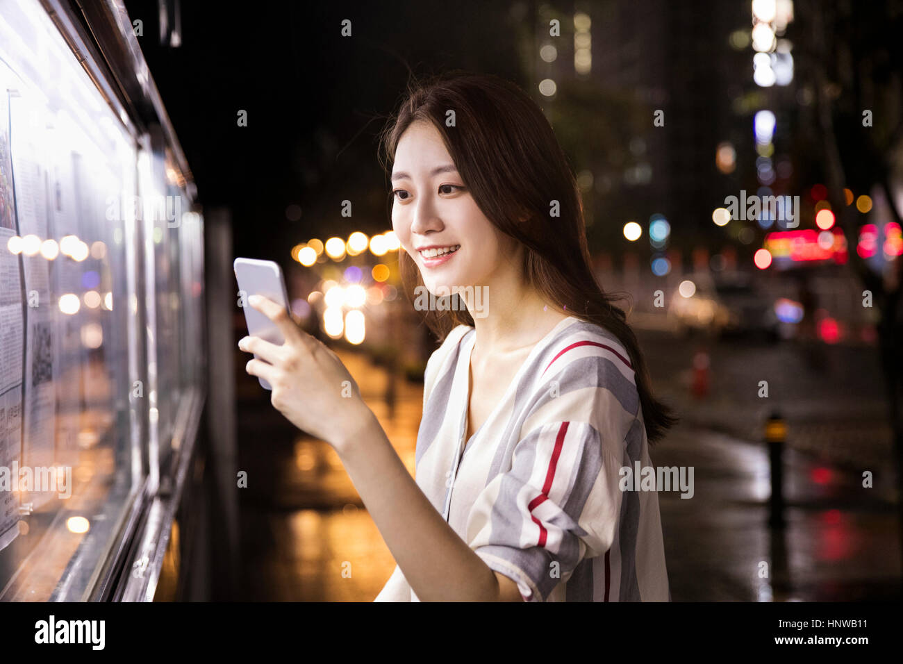 Young smiling woman in city at night Stock Photo - Alamy