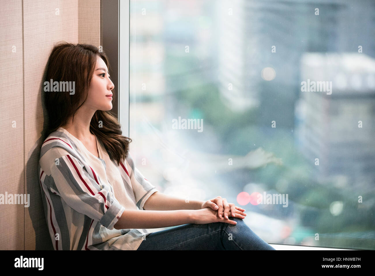 Young woman sitting at window Stock Photo - Alamy