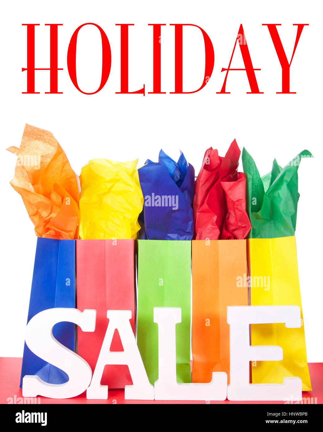 colorful bags with bright tissue paper inserts on a red table with ...