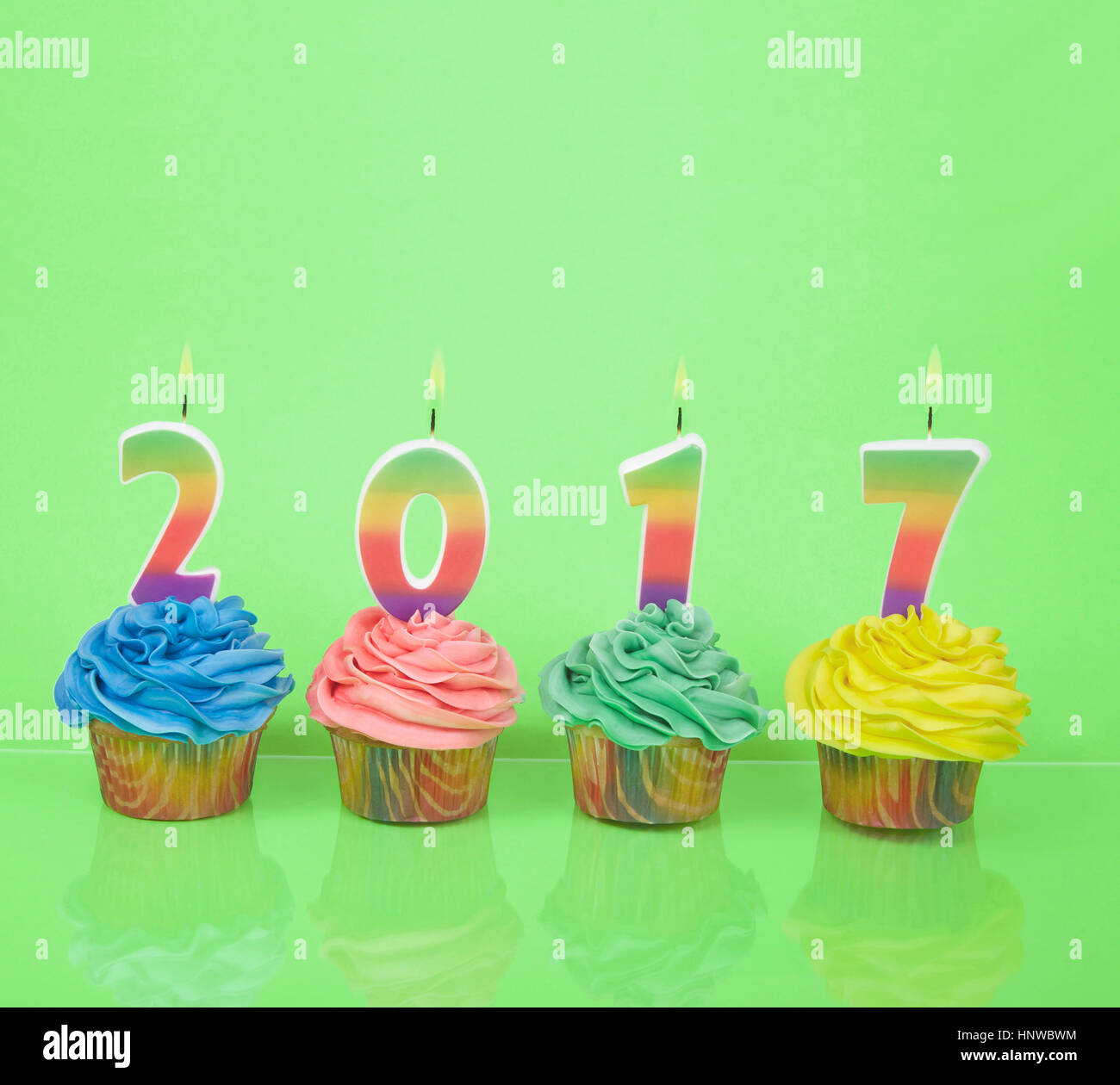 Rainbow colored bright blue, pink, red, green, yellow cup cakes on a ...