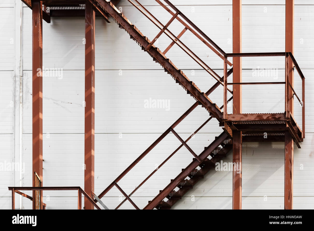 Old rusty metal ladder against a white wall background. Metal steps ...