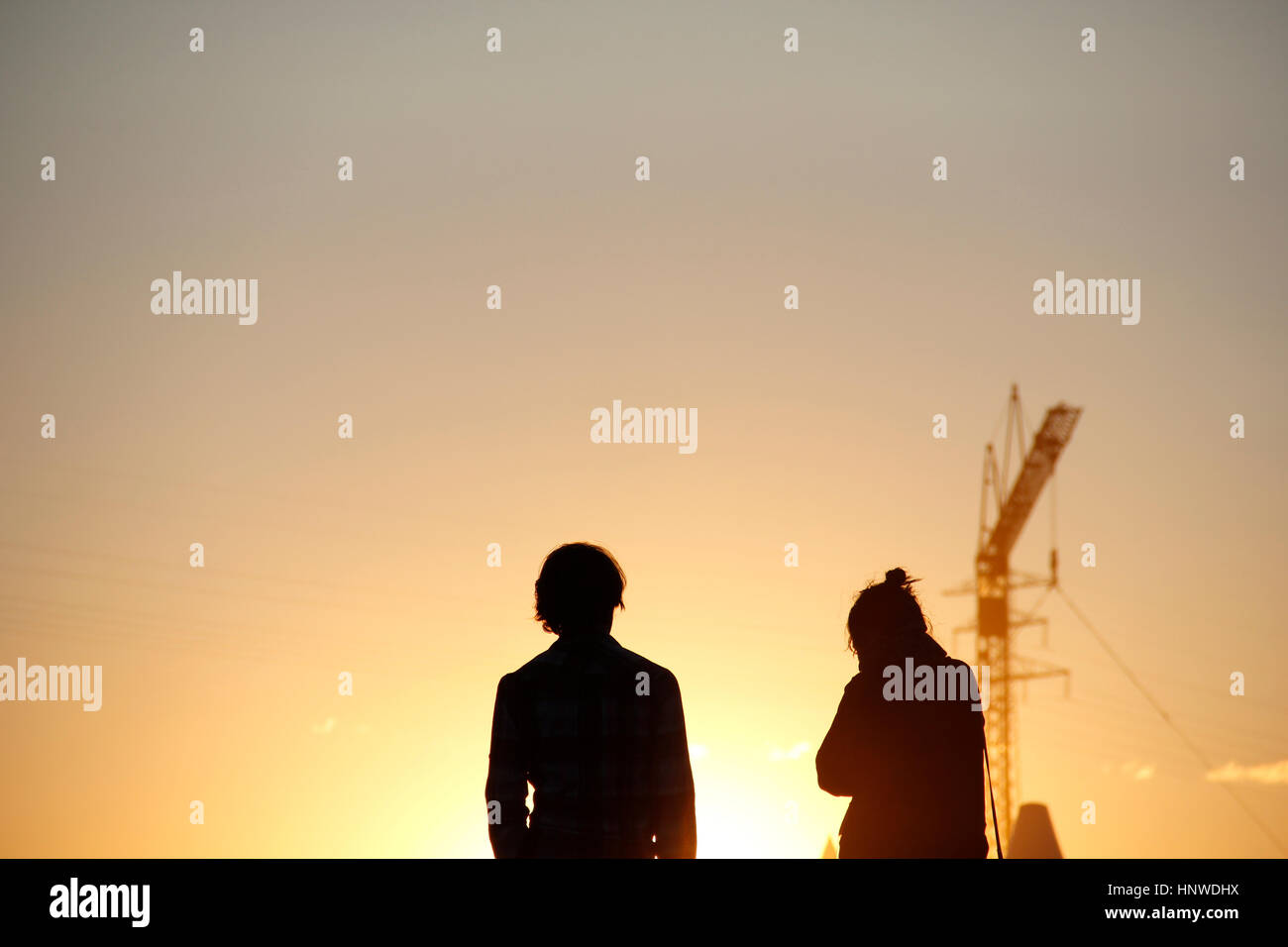 Silhouette of two young people watching the sunset at the harbour Stock ...