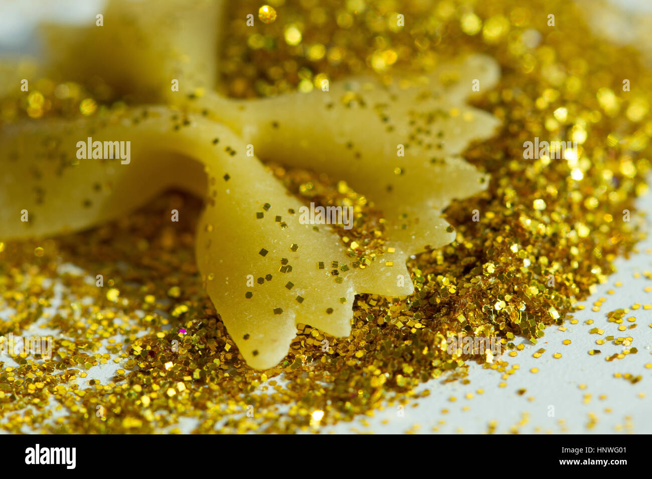 Pasta bow shape with golden tinsels and white background Stock Photo ...