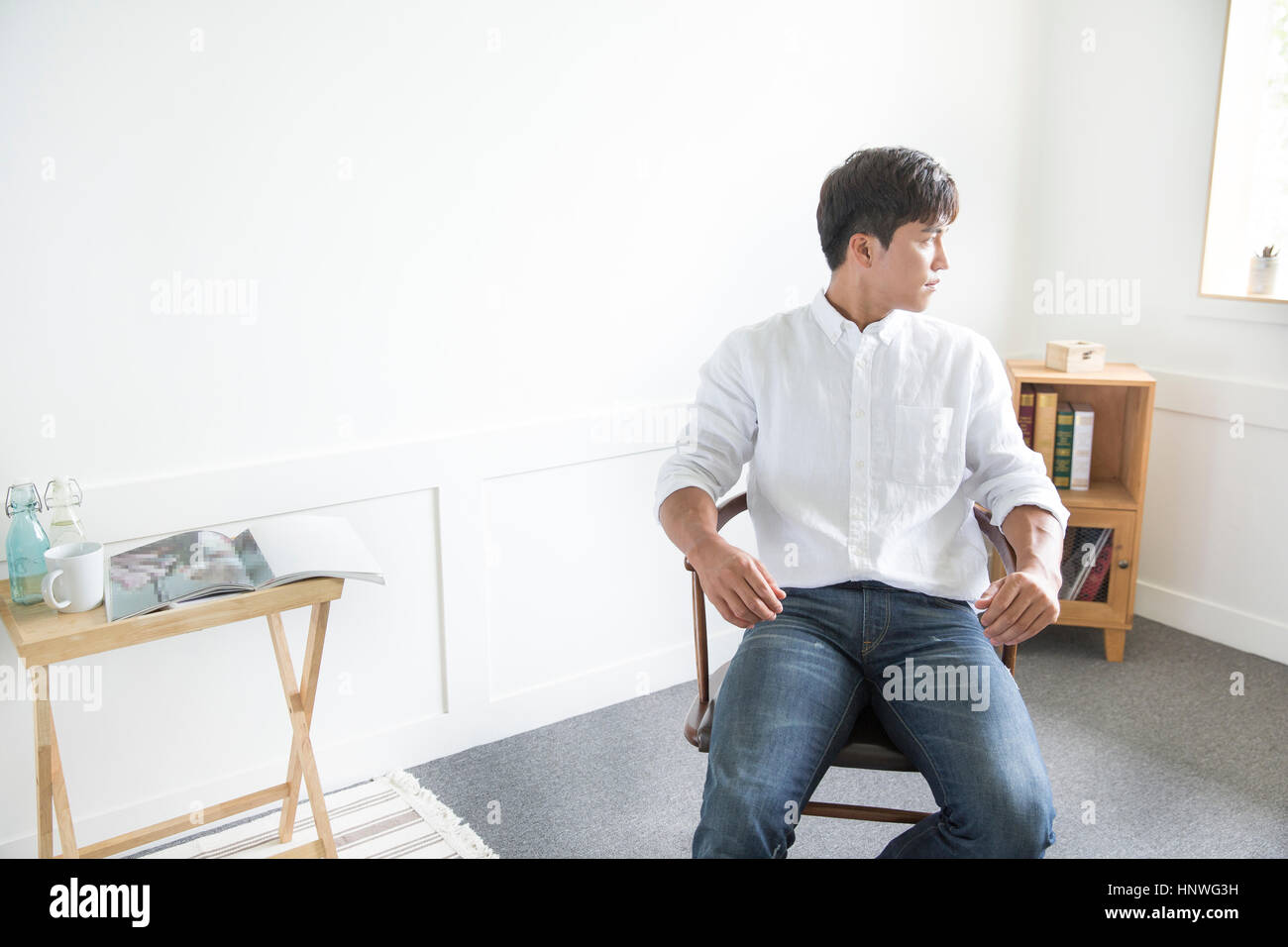 Smiling man looking aside sitting on chair Stock Photo - Alamy