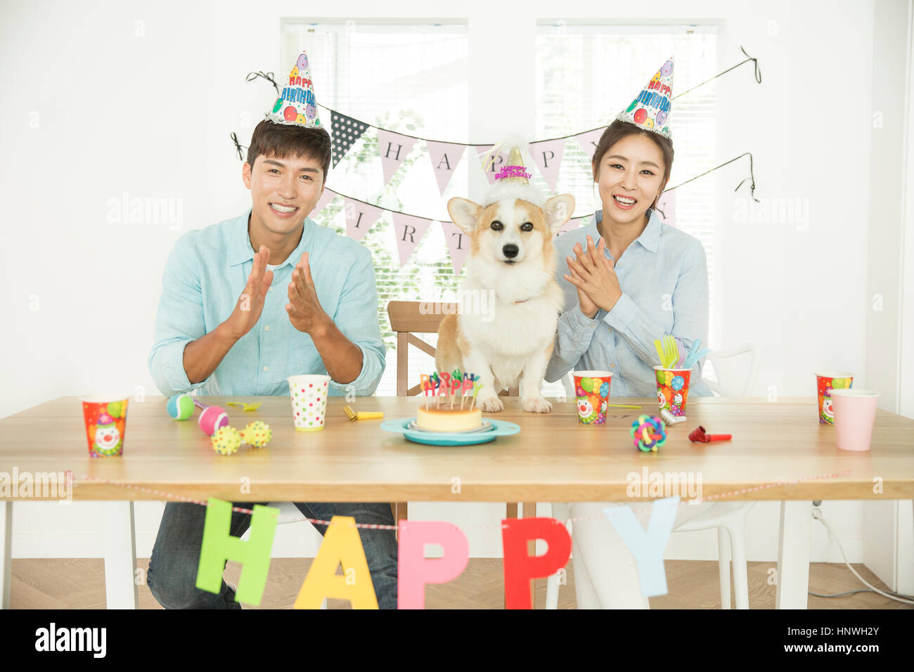 Smiling couple celebrating pet's birthday Stock Photo - Alamy