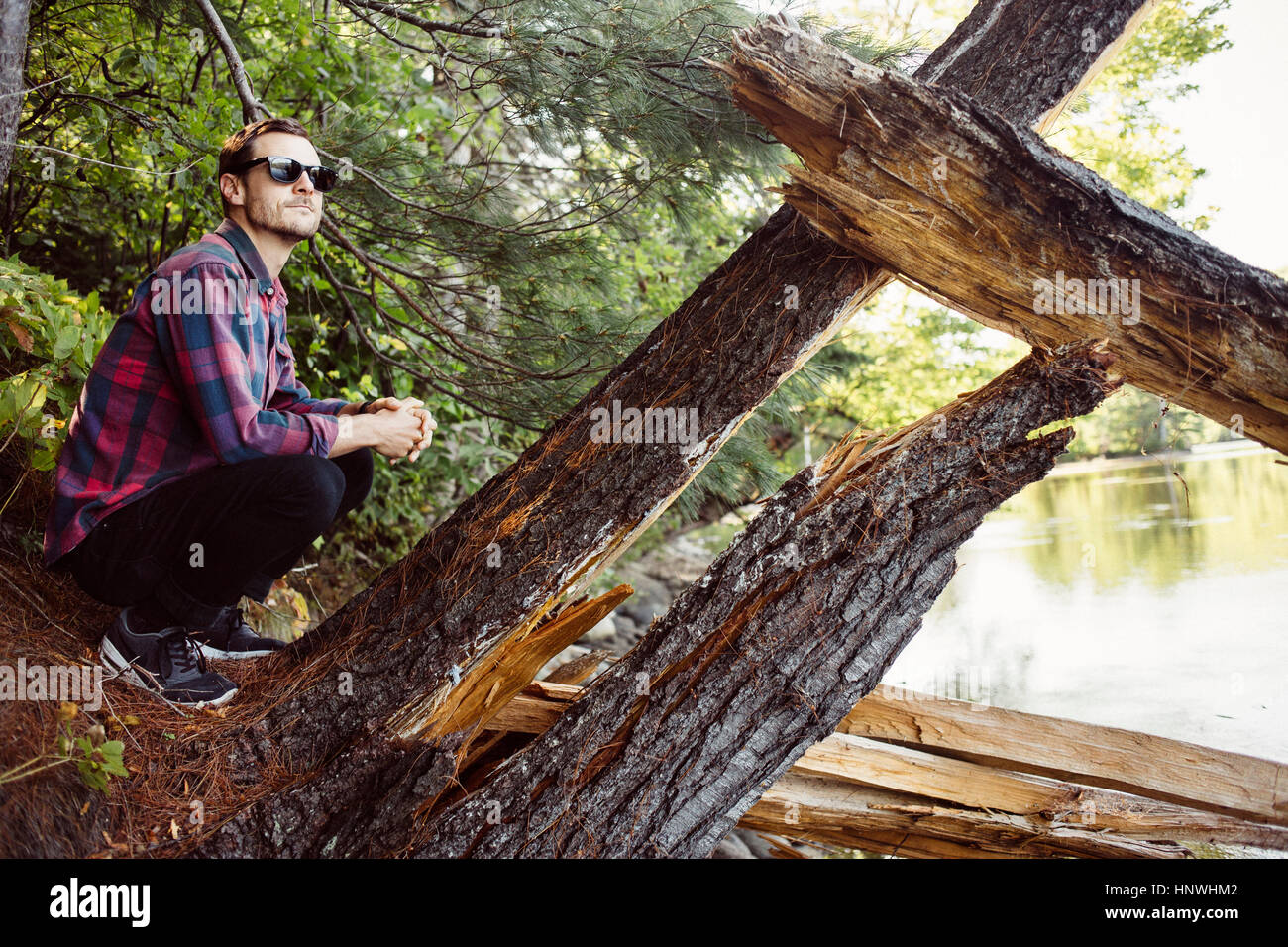 Man crouching beside lake Stock Photo - Alamy