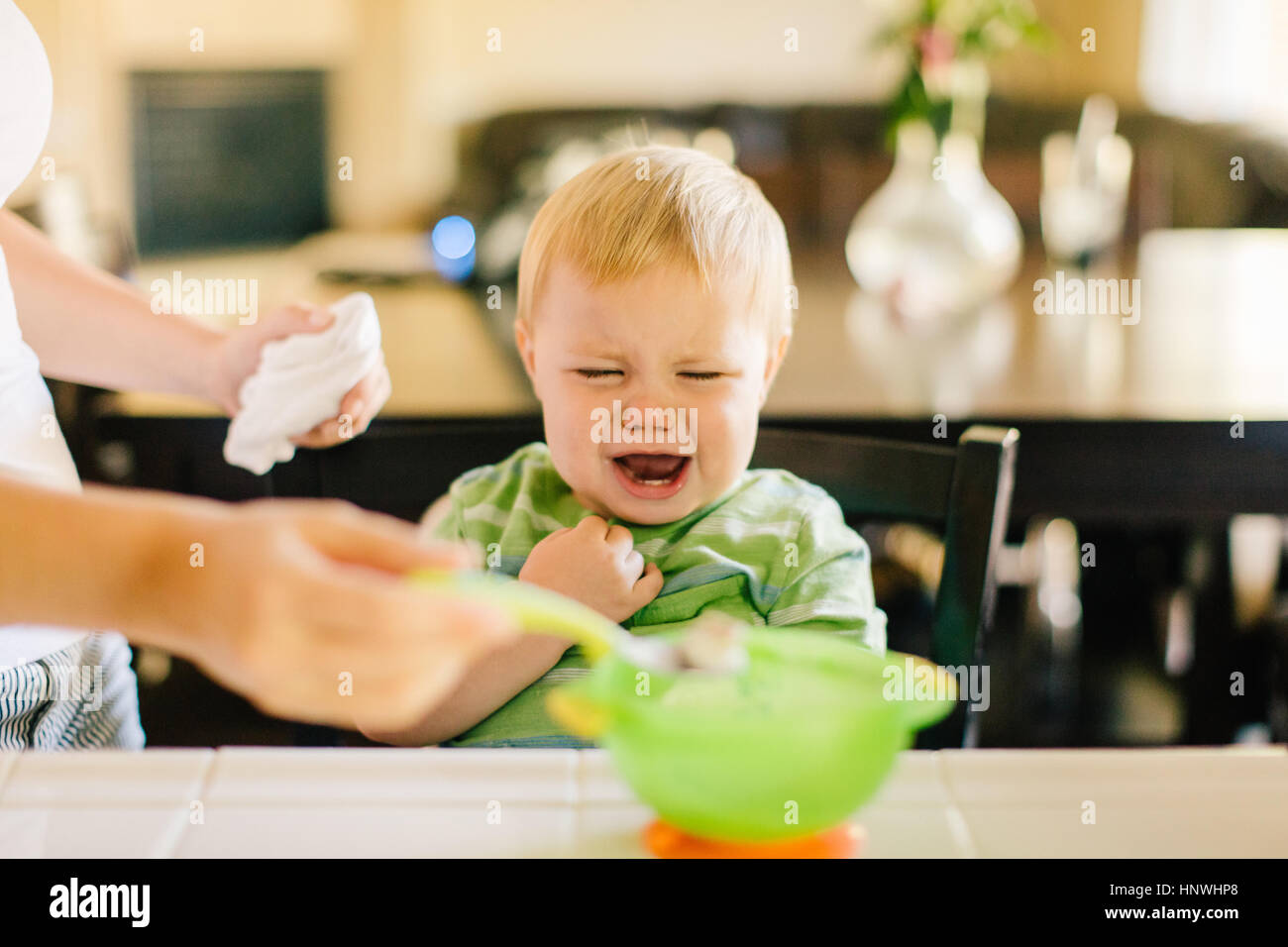 Mother helping young son eat breakfast, son crying, mid section Stock ...