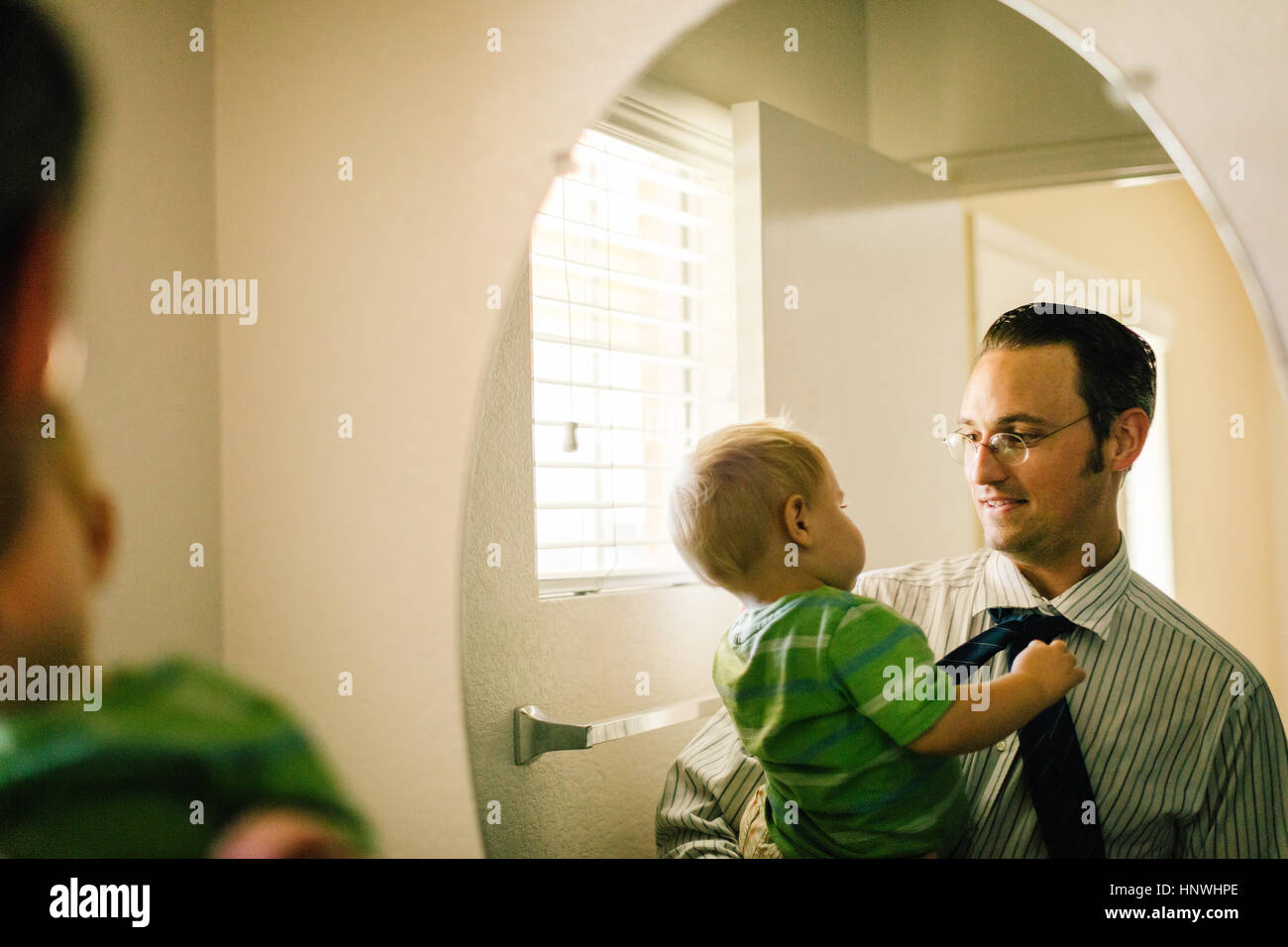 Father holding young son, reflected in mirror Stock Photo - Alamy