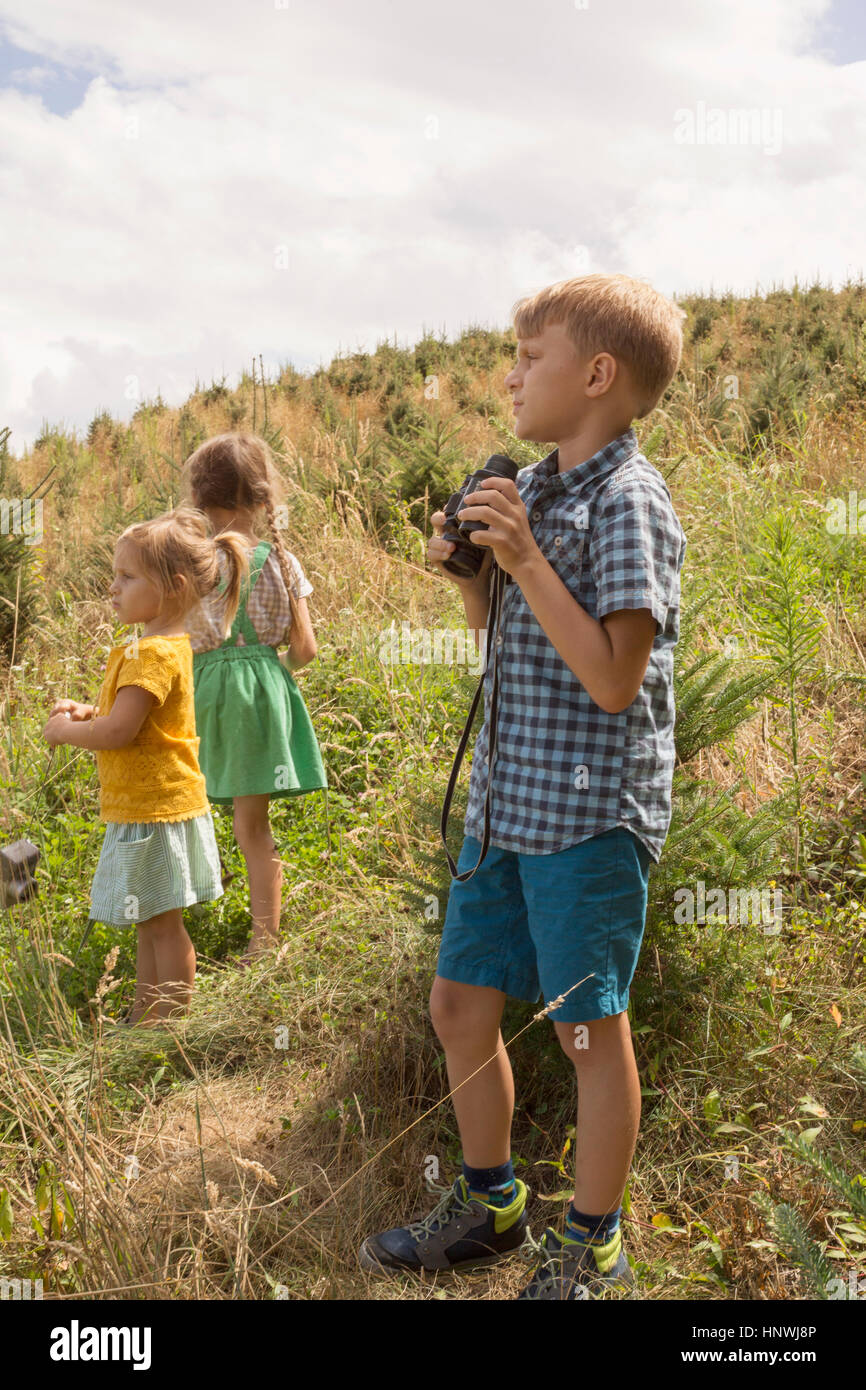 Three young children exploring, outdoors, boy using binoculars Stock ...