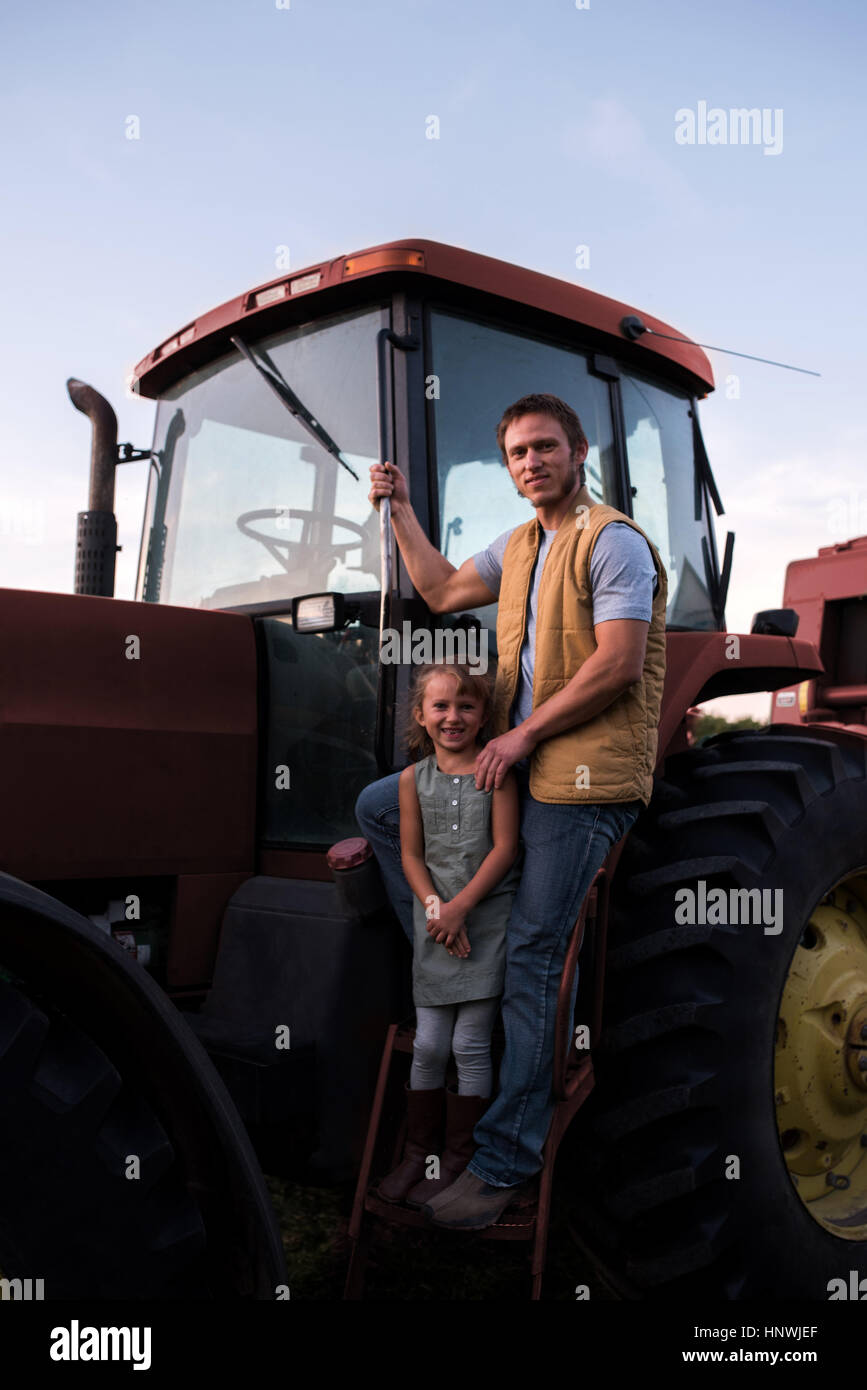 Portrait of father and daughter beside tractor Stock Photo - Alamy