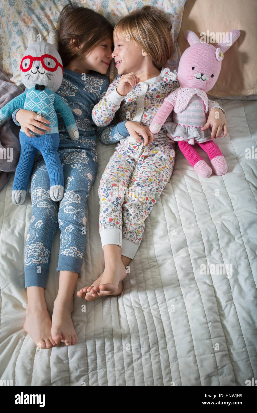 Sisters hugging soft toys on bed Stock Photo - Alamy