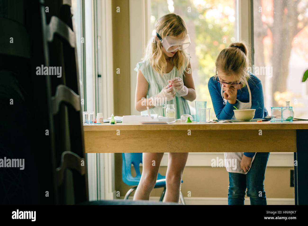 Two girls doing science experiment, reading chemistry set instructions ...