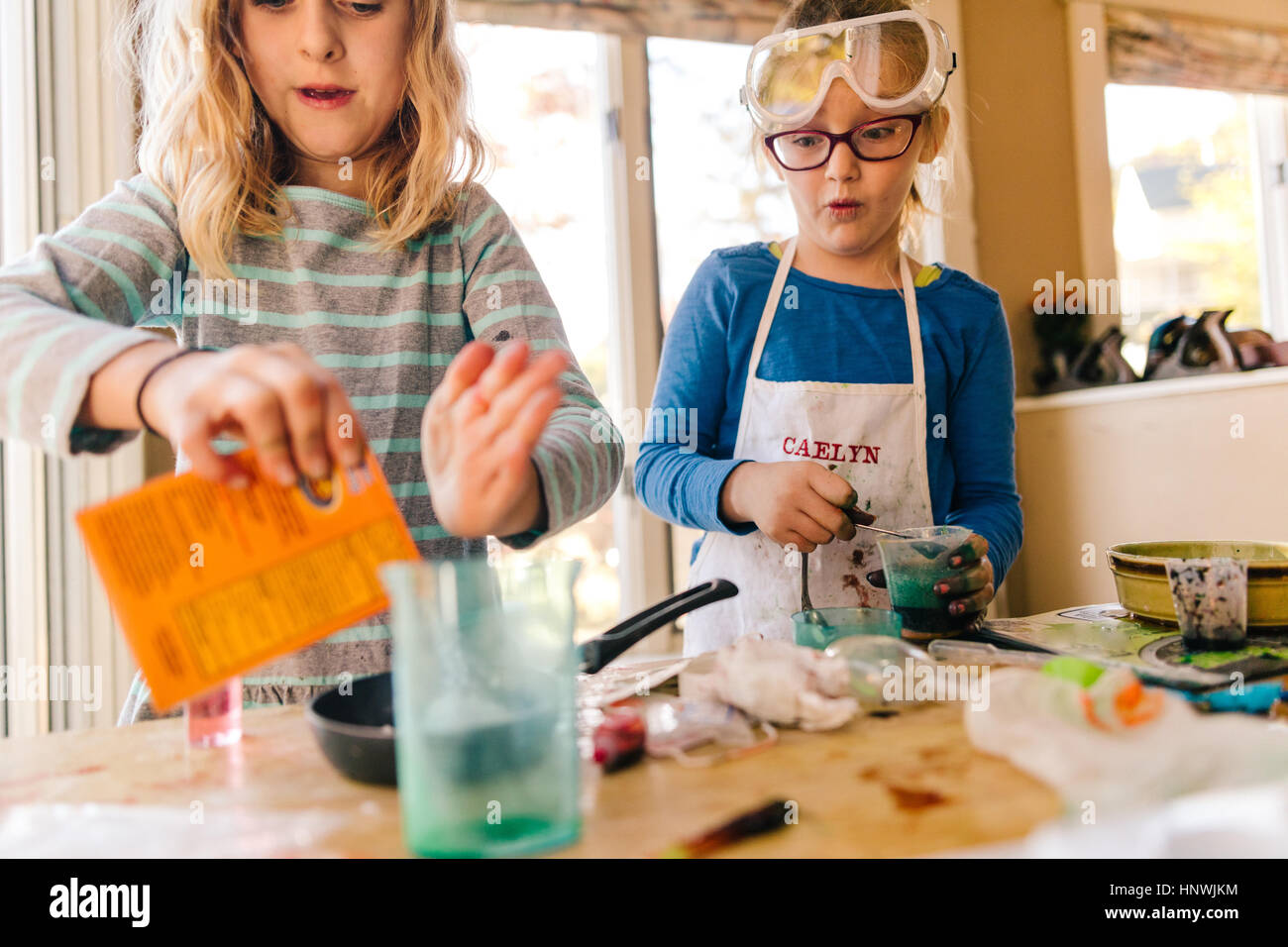 Two girls doing science experiment, pouring packet into frying pan ...