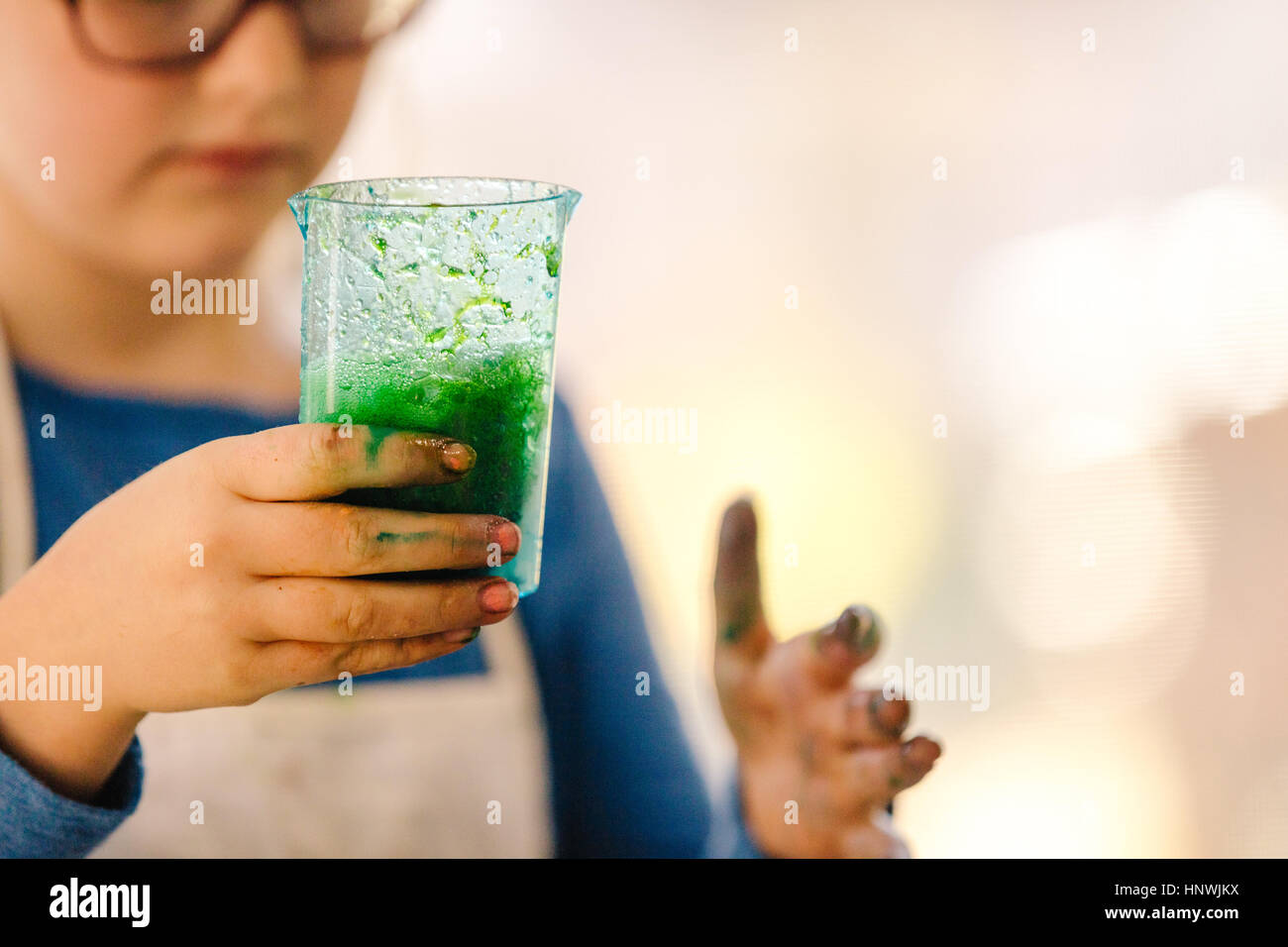Girl doing science experiment, holding flask of green liquid Stock ...
