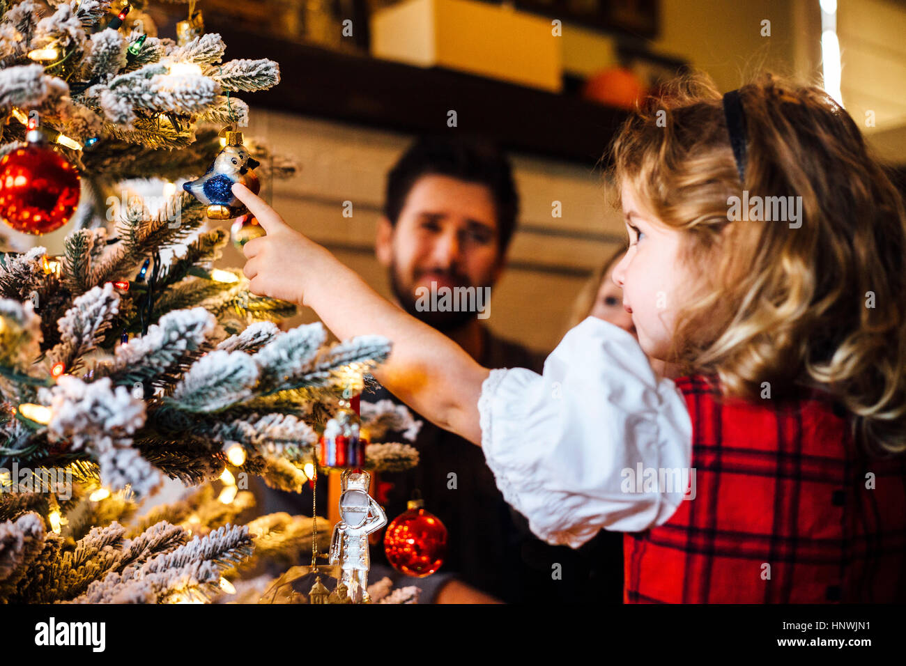 Female toddler with parents pointing at christmas tree bauble Stock ...