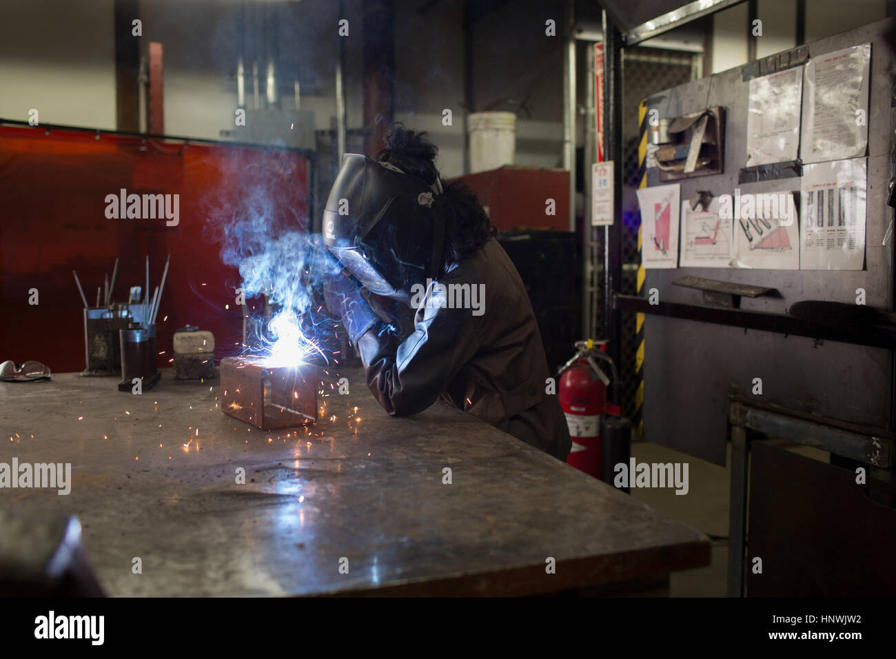 Female metalsmith welding metal box on workbench Stock Photo - Alamy