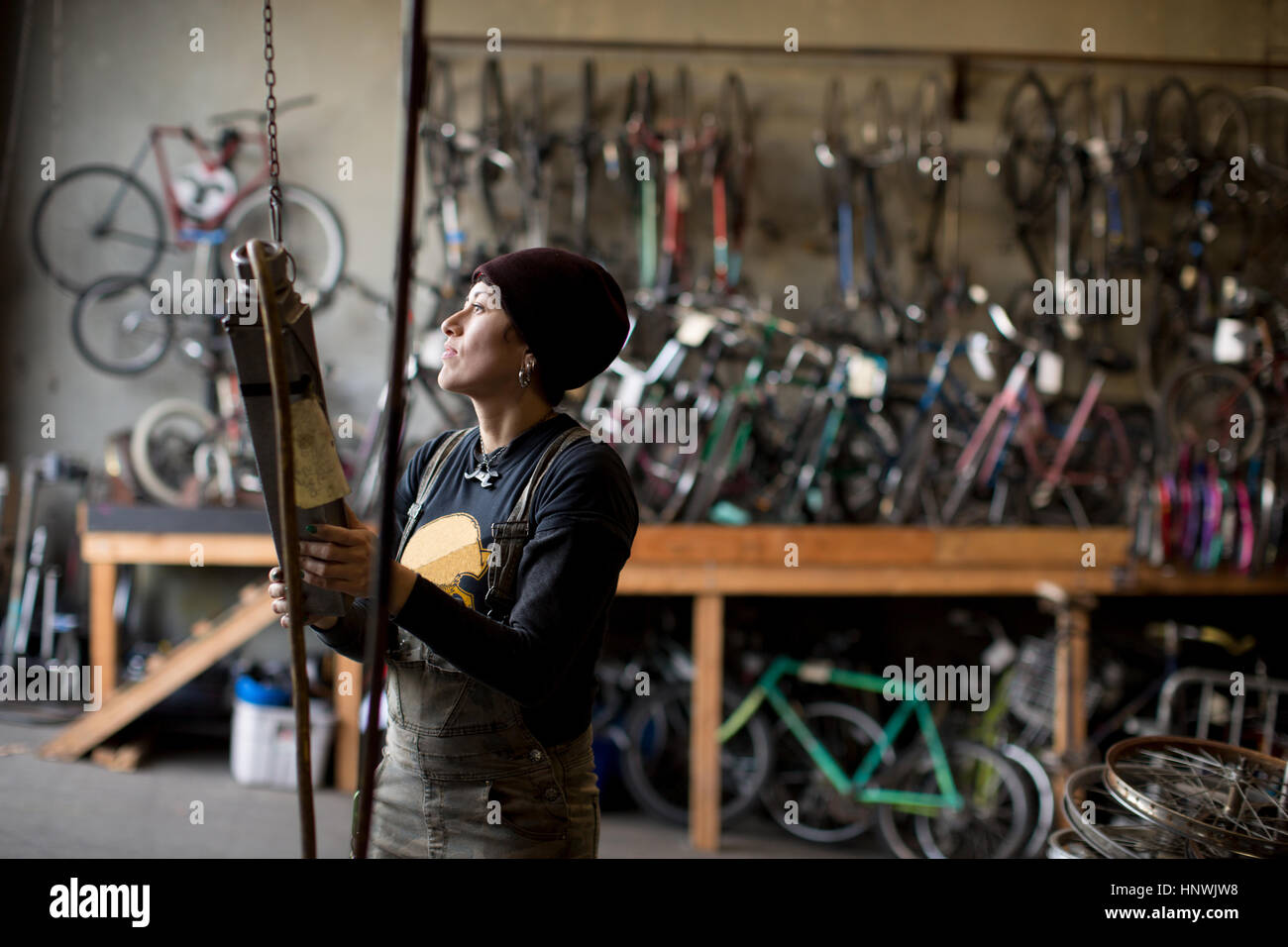 Female metalsmith attaching metal to chain hoist in workshop Stock ...