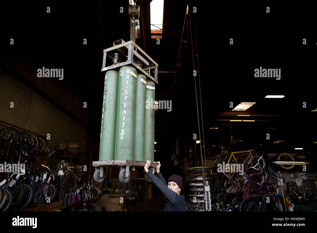 Portrait of female metalsmith steadying chain hoist in workshop Stock ...