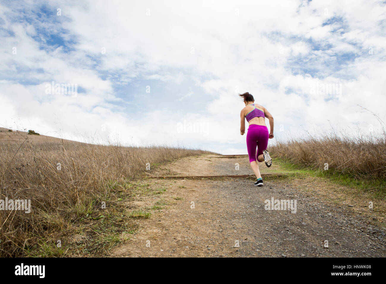 Rear view of female runner running up dirt track Stock Photo - Alamy