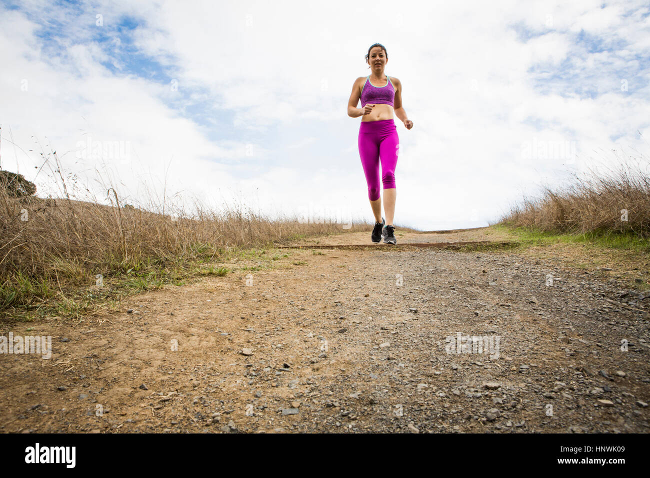 Female runner running down dirt track Stock Photo - Alamy