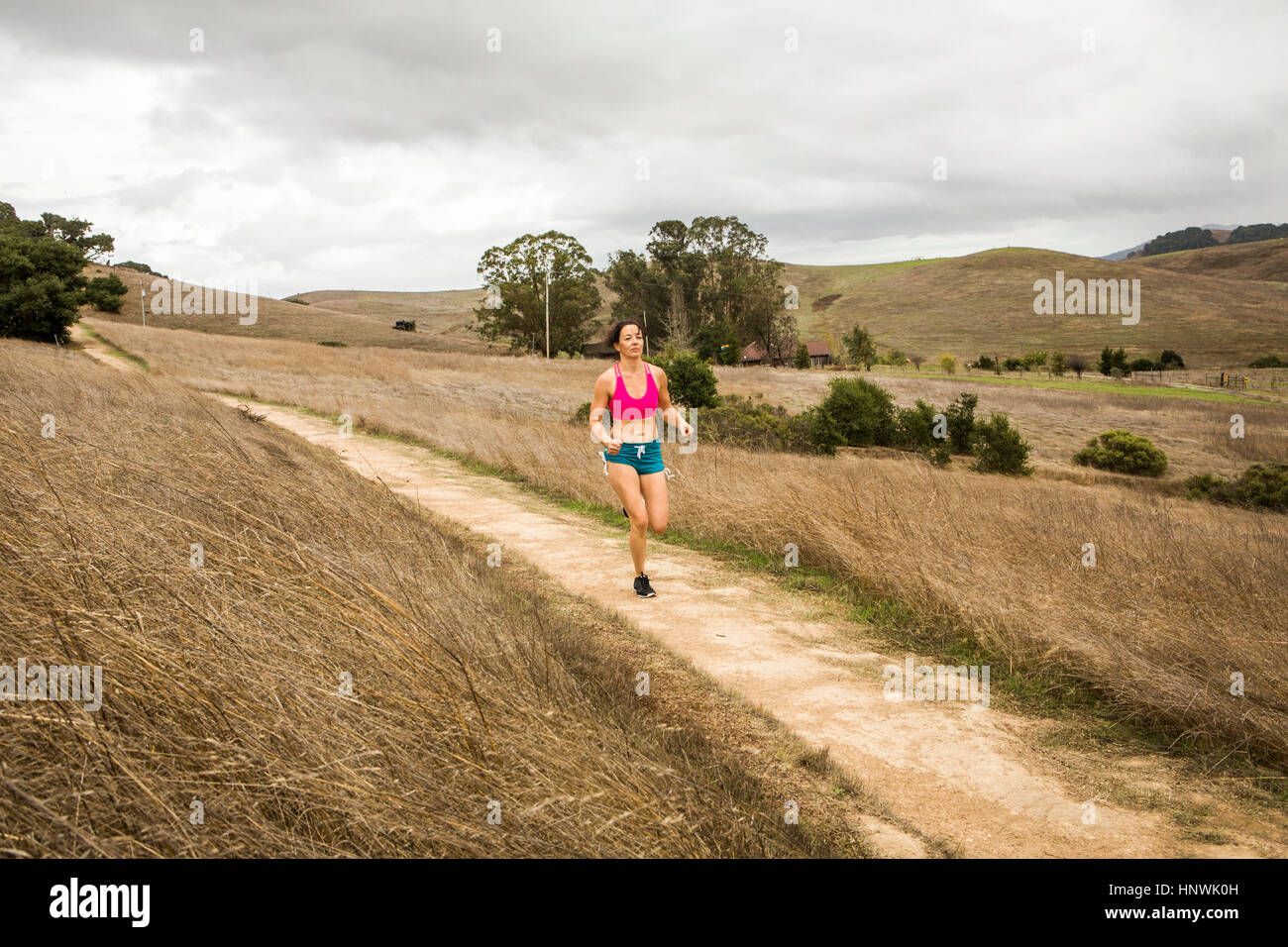 Female runner running on dirt track in landscape Stock Photo - Alamy