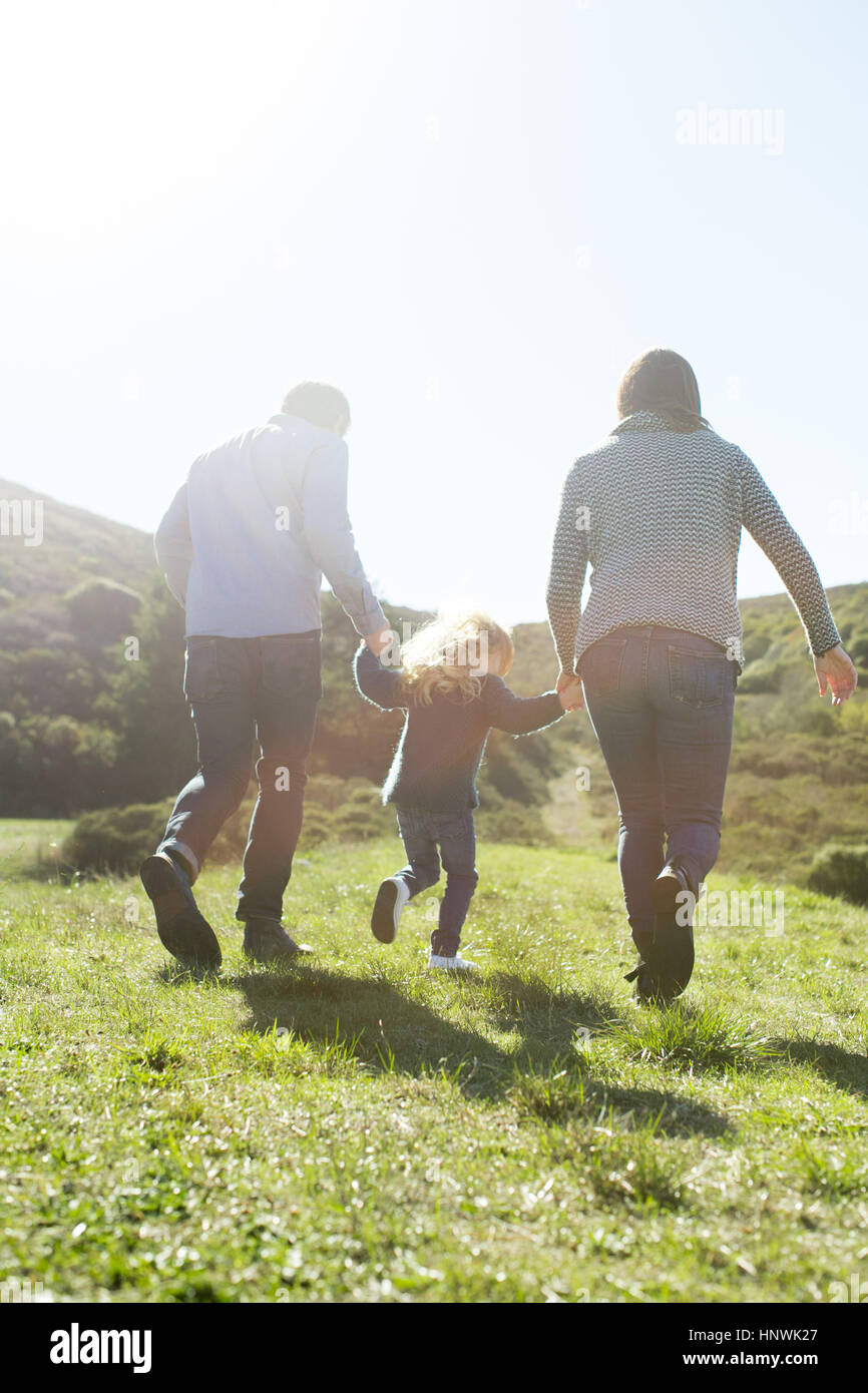 Rear view of mid adult couple and daughter strolling in field Stock ...